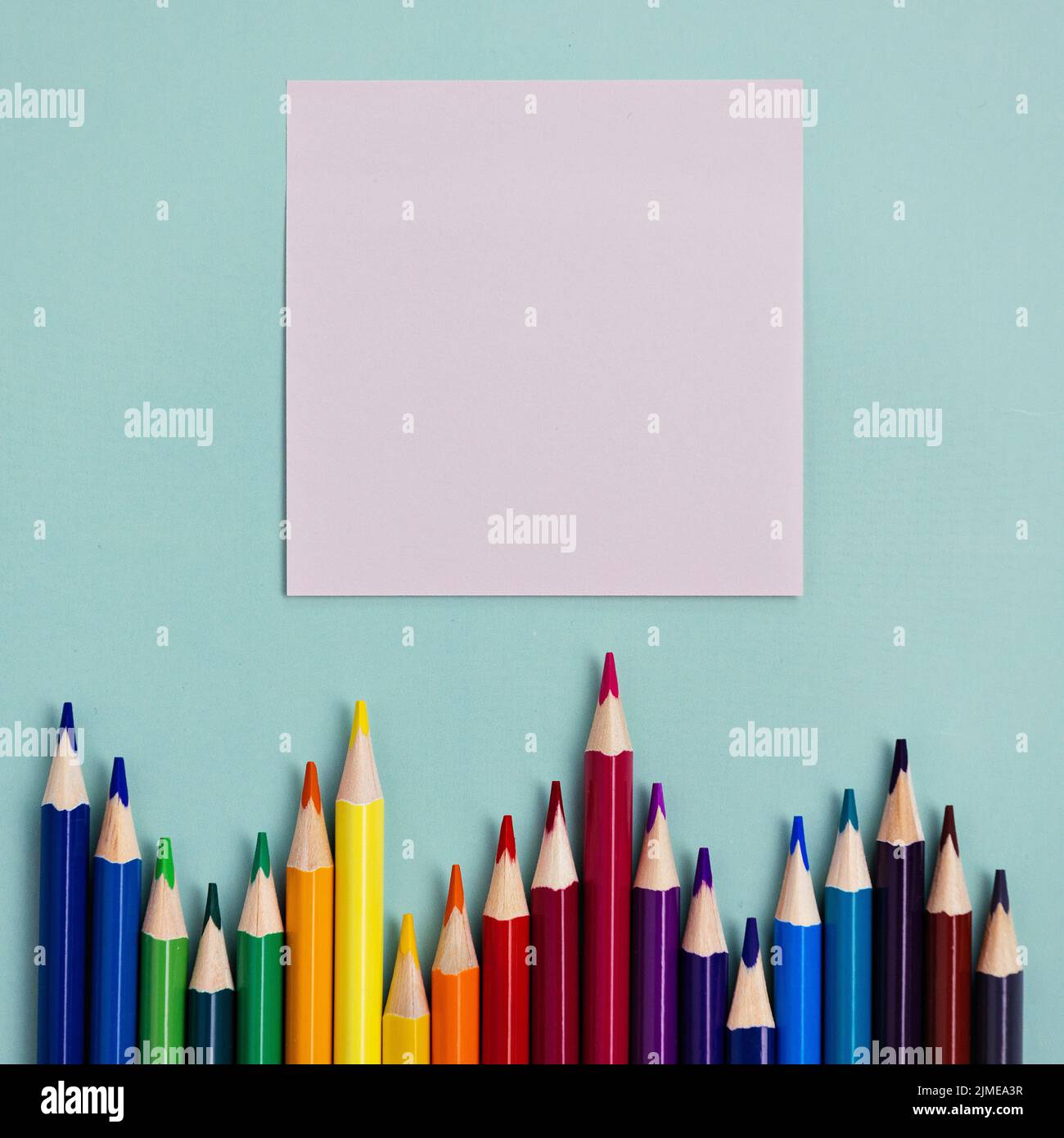Colored pencils and a sheet for notes lie on a blue background. Top ...