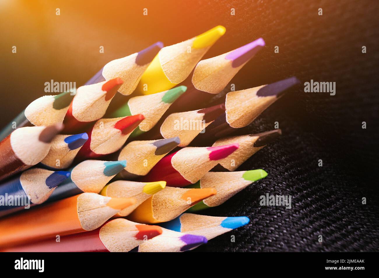 New color sharpened pencils on a dark background with sunlight or ...