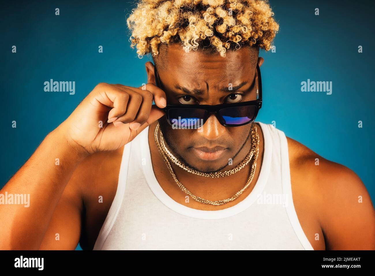 A swarthy guy with a fashionable hairstyle with pigtails Looks straight ...