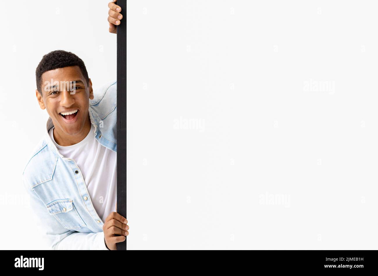 Young African American man peeking out from empty white board Copy ...