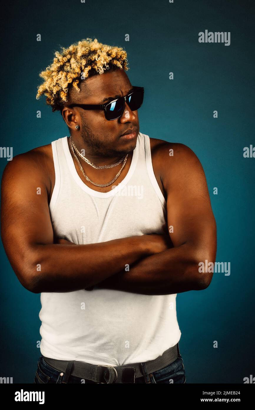 A swarthy guy with a fashionable hairstyle with pigtails keeps his ...