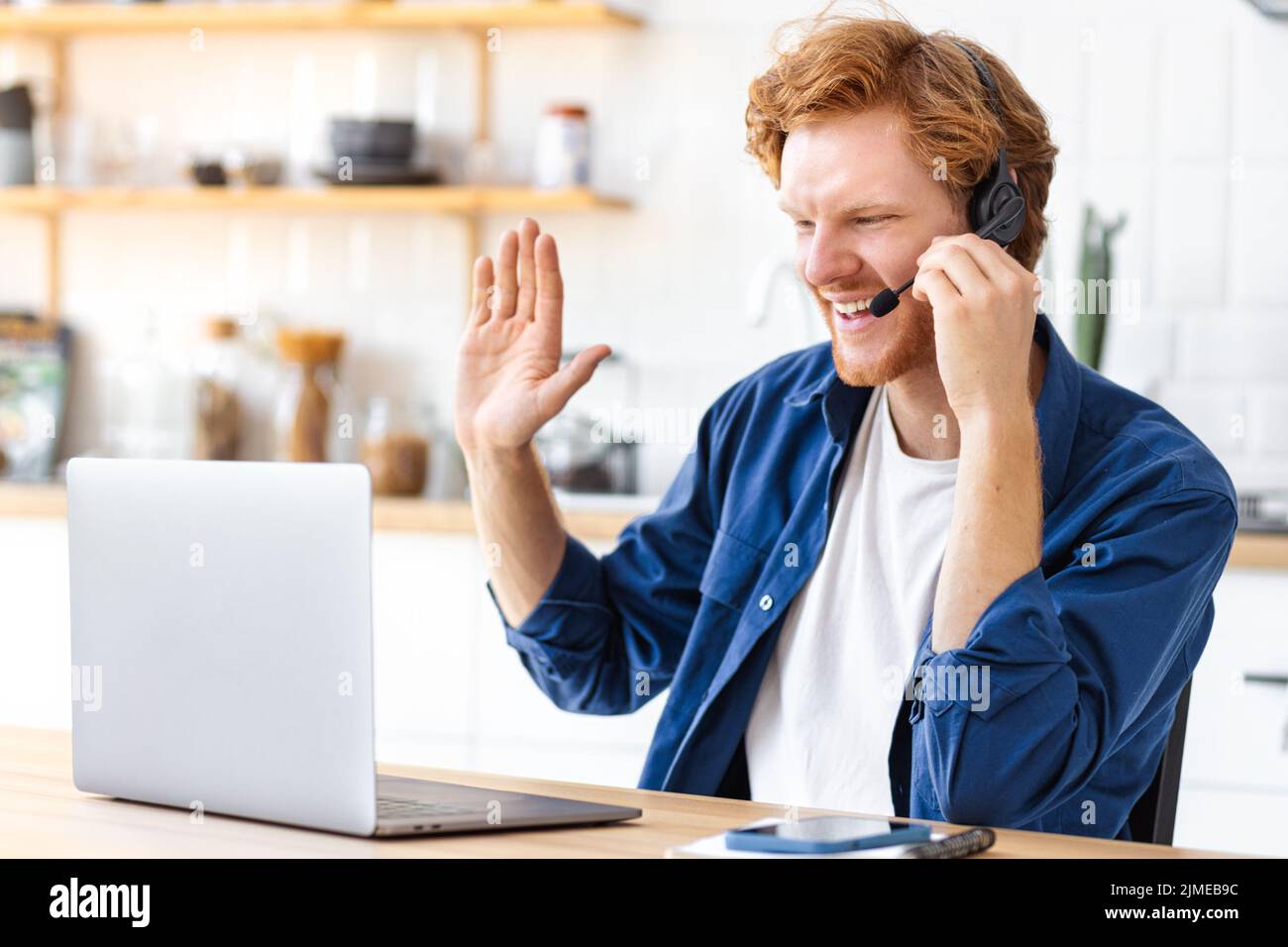 Young happy man student in headset using laptop sitting in home having ...