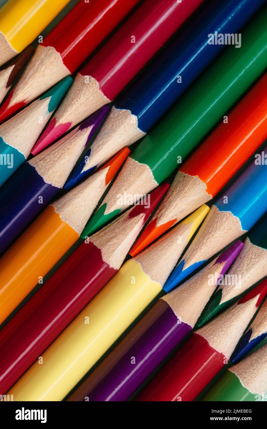Colored sharpened pencils lie in a row close-up. Solid abstract background of wooden multi ...