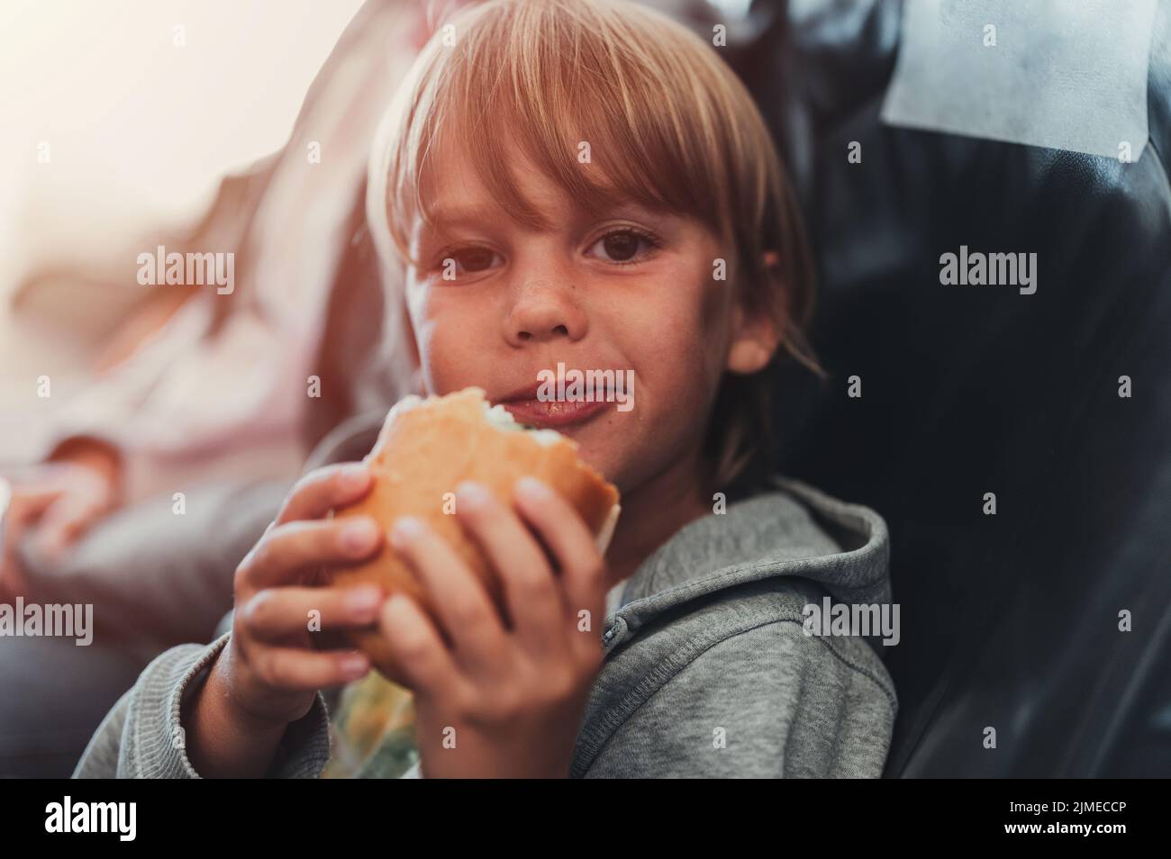 little candid kid boy five years old eats burger or sandwich food ...