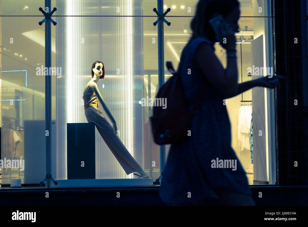Silhouette of woman passing by a mannequin in shop window Stock Photo ...