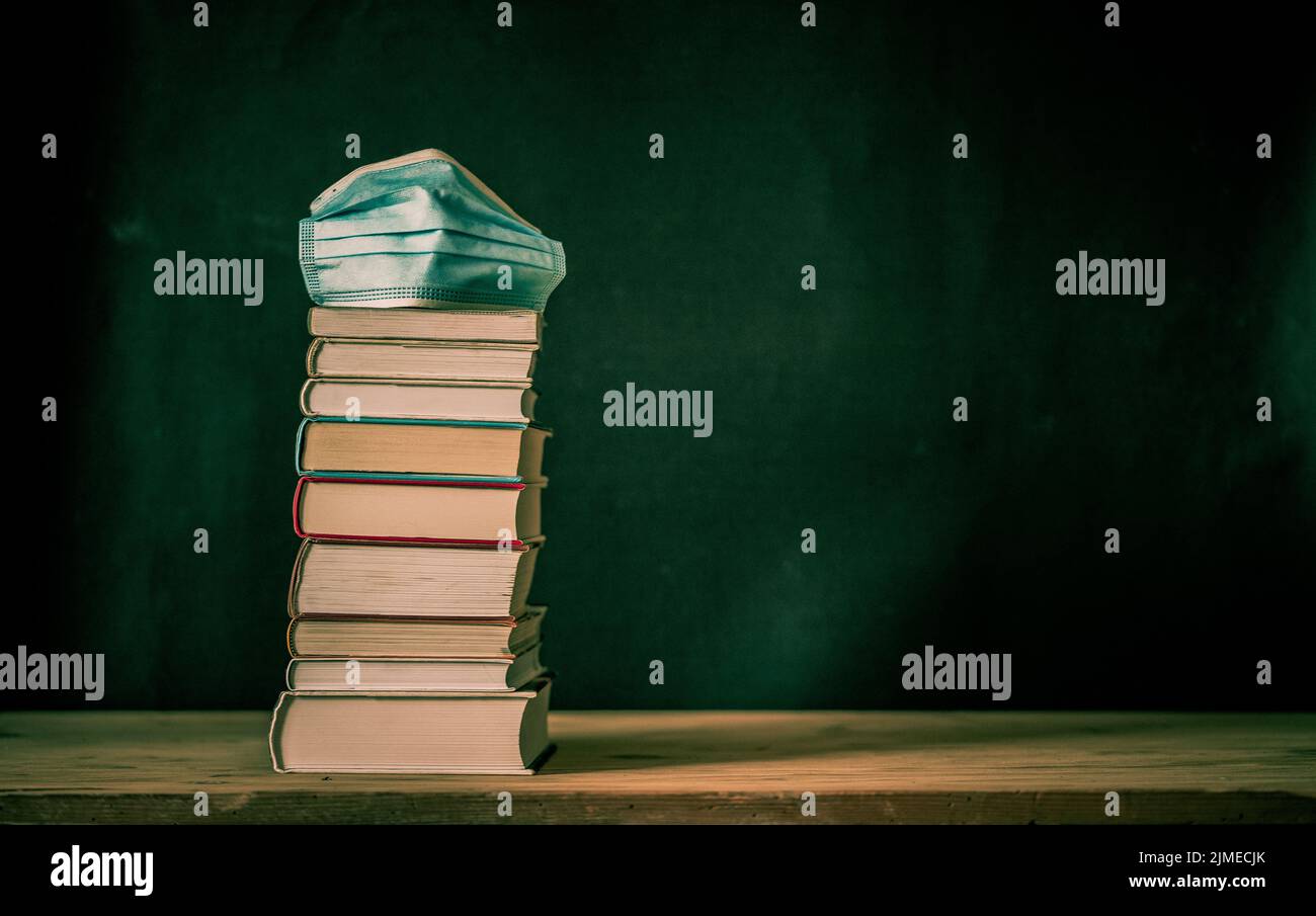 Back to school during covid pandemic pile of books and medical mask ...