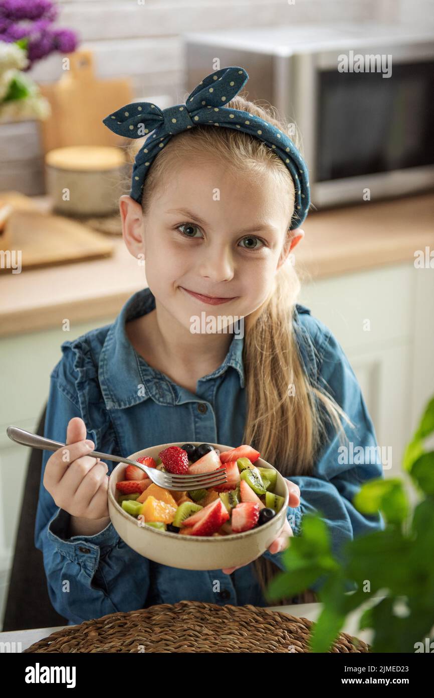 Healthy food at home. Cute little girl eats fruit salad Stock Photo - Alamy