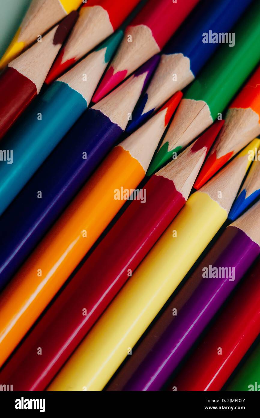 Colored sharpened pencils lie in a row close-up. Solid abstract background of wooden multi ...