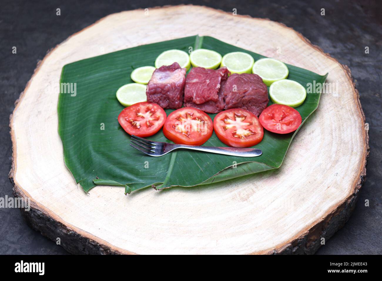 fresh tasty cow beef with sliced lemon and spoon on banana leaf Stock ...