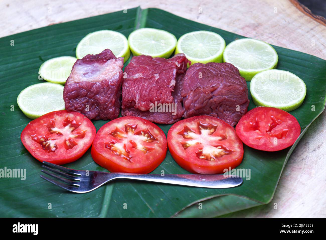 fresh tasty cow beef with sliced lemon and spoon on banana leaf Stock ...