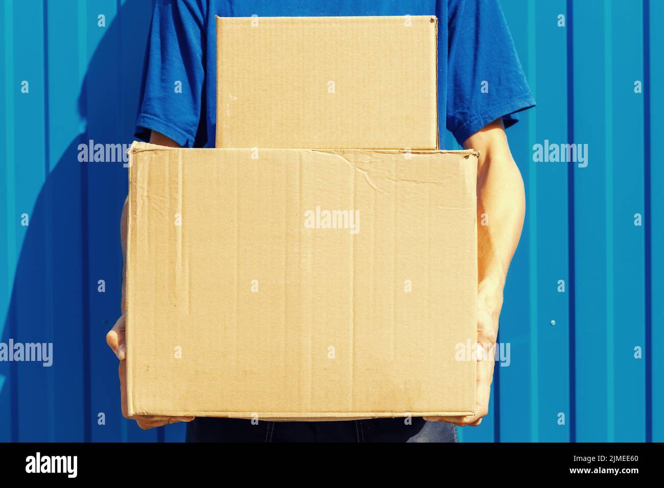 The courier holds cardboard boxes in his hands. Close-up with space to ...