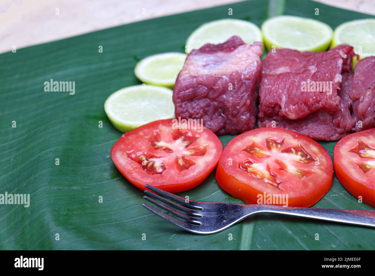 fresh tasty cow beef with sliced lemon and spoon on banana leaf Stock ...
