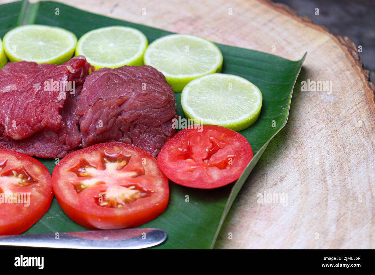 fresh tasty cow beef with sliced lemon and spoon on banana leaf Stock ...
