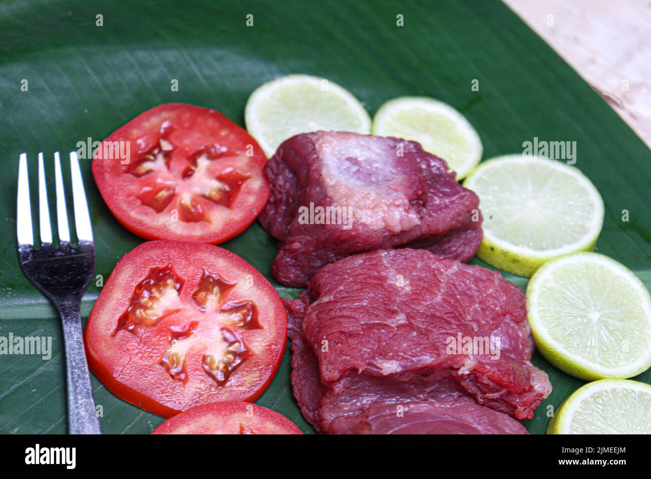 fresh tasty cow beef with sliced lemon and tomato on banana leaf Stock ...
