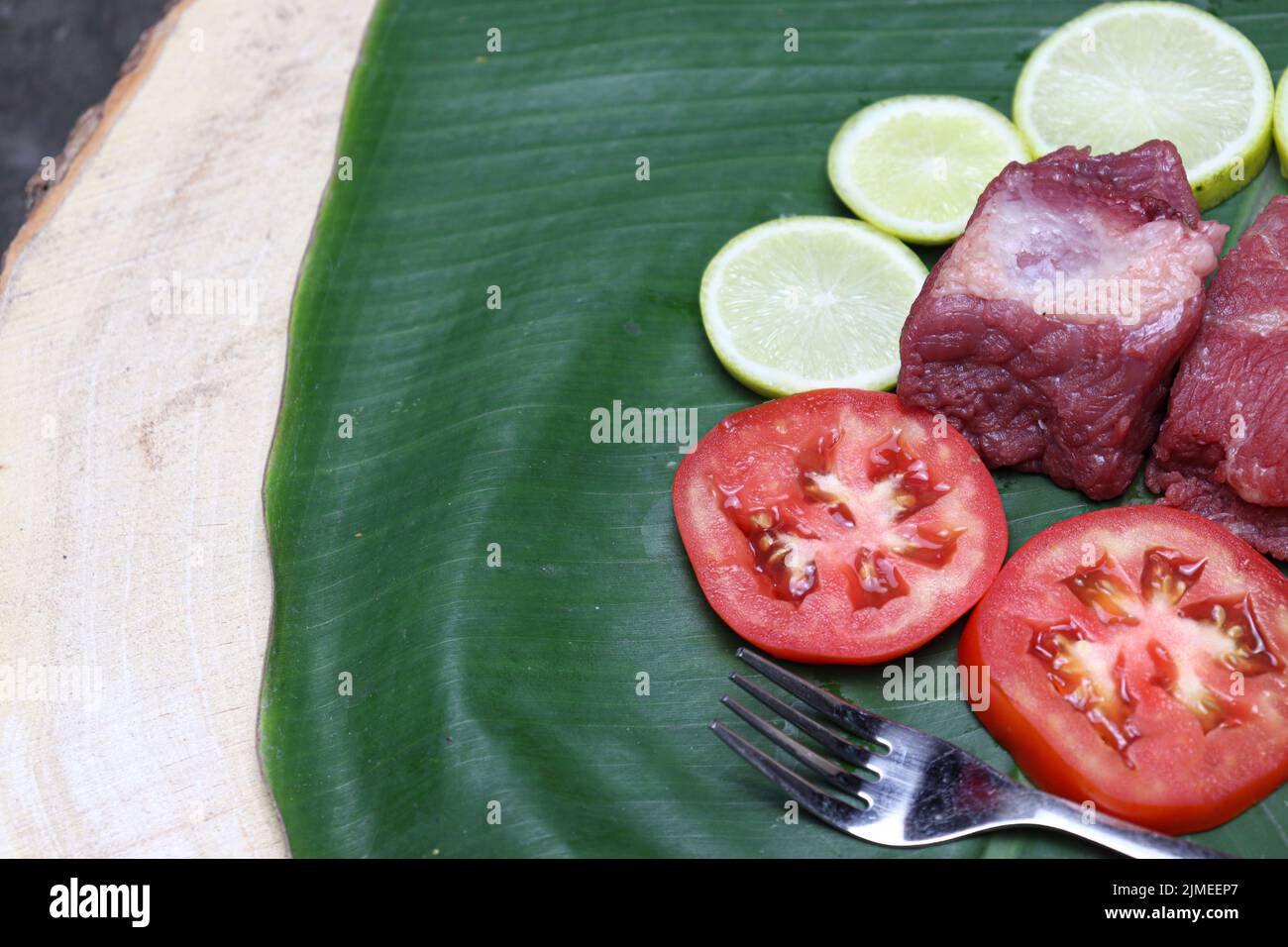 fresh tasty cow beef with sliced lemon and spoon on banana leaf Stock ...