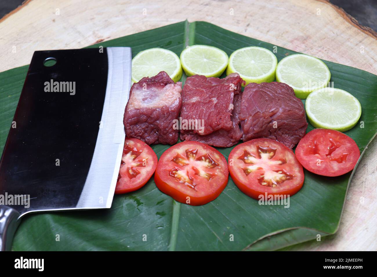 fresh tasty cow beef with sliced lemon and tomato on banana leaf Stock ...