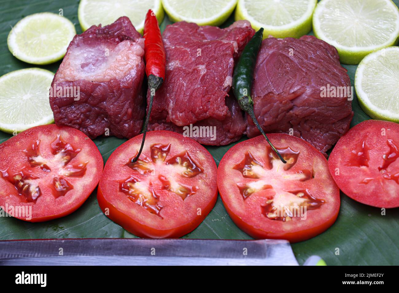 fresh tasty cow beef with sliced lemon and tomato on banana leaf Stock ...
