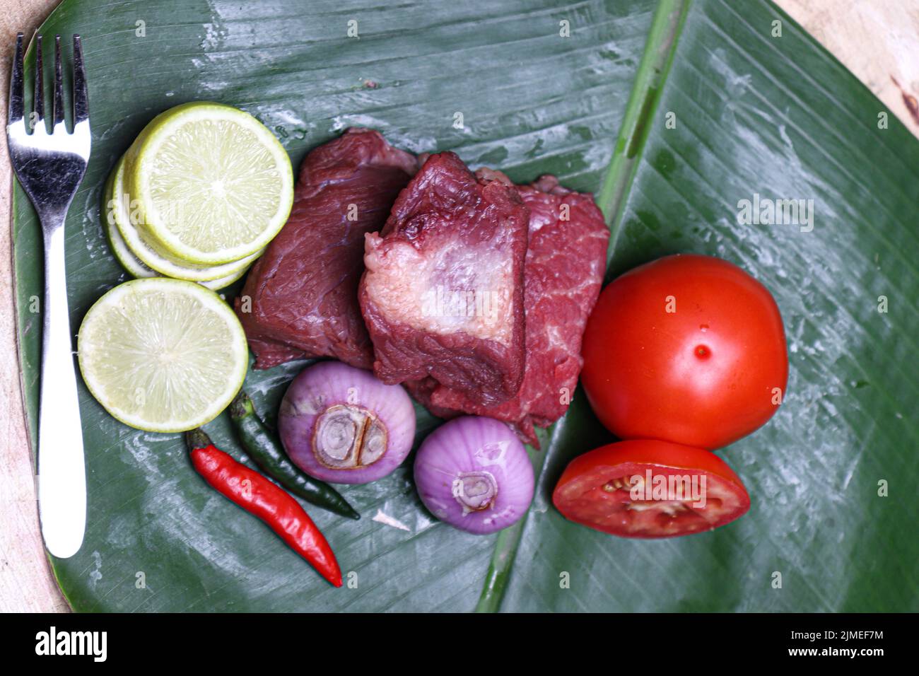 fresh tasty cow beef with sliced lemon and tomato on banana leaf Stock ...