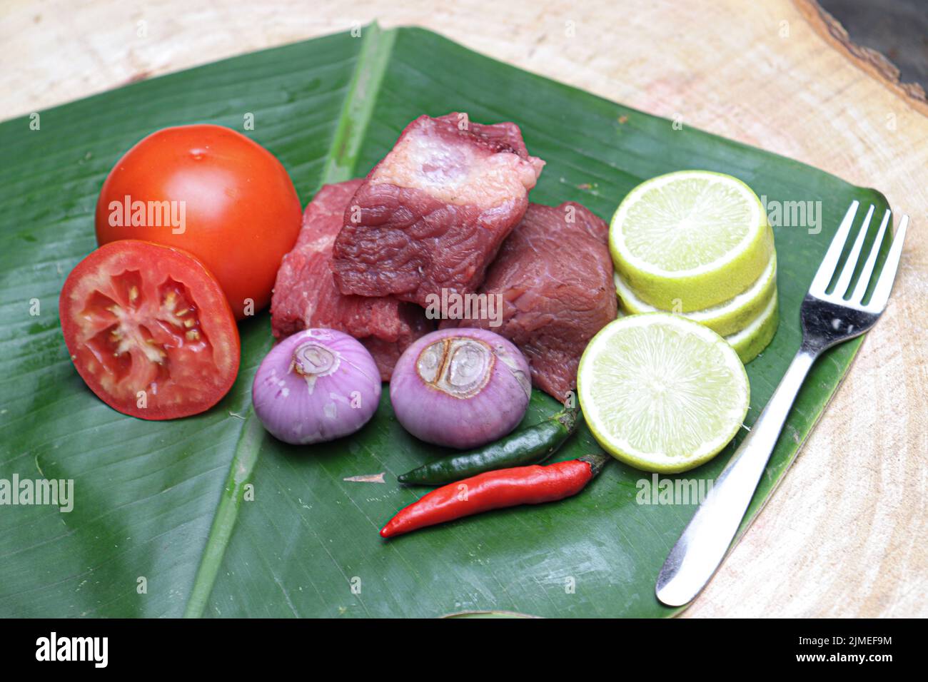 fresh tasty cow beef with sliced lemon and tomato on banana leaf Stock ...