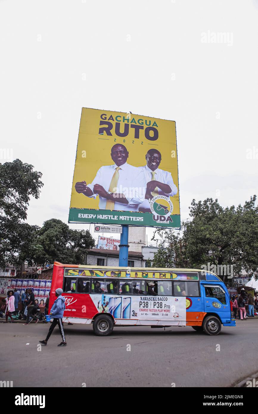 A Matatu (Mini bus) passes near a political campaign billboard with a ...