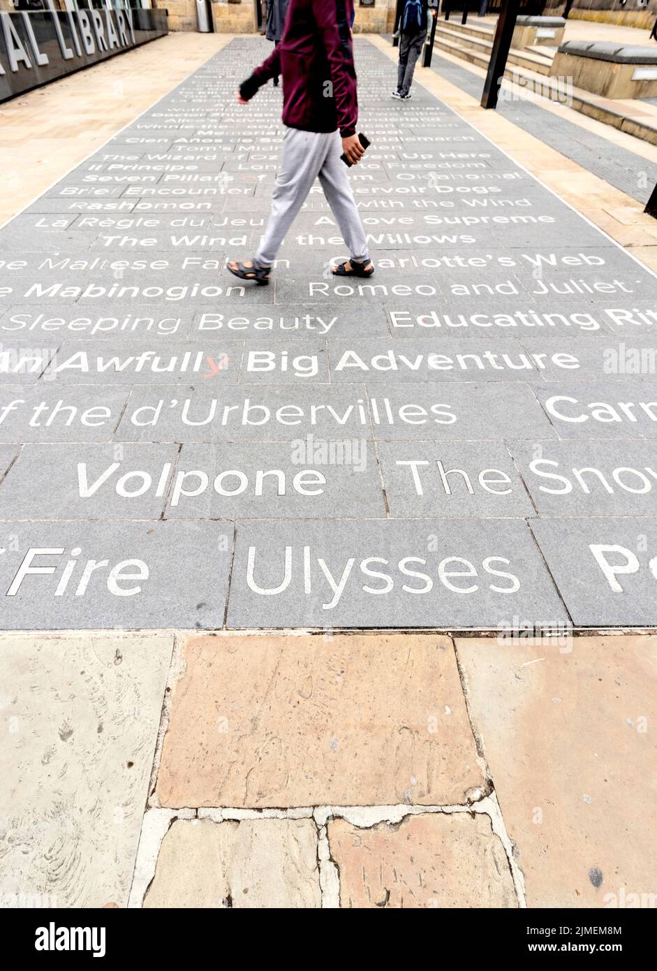 A close-up view of man walking over paving with engraved names of ...