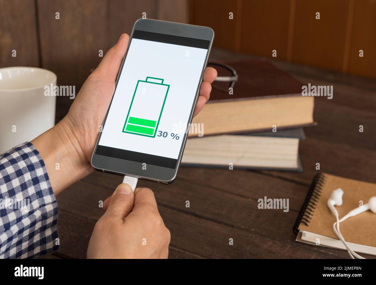Hipter is plugged in to charging mobile smartphones Stock Photo - Alamy