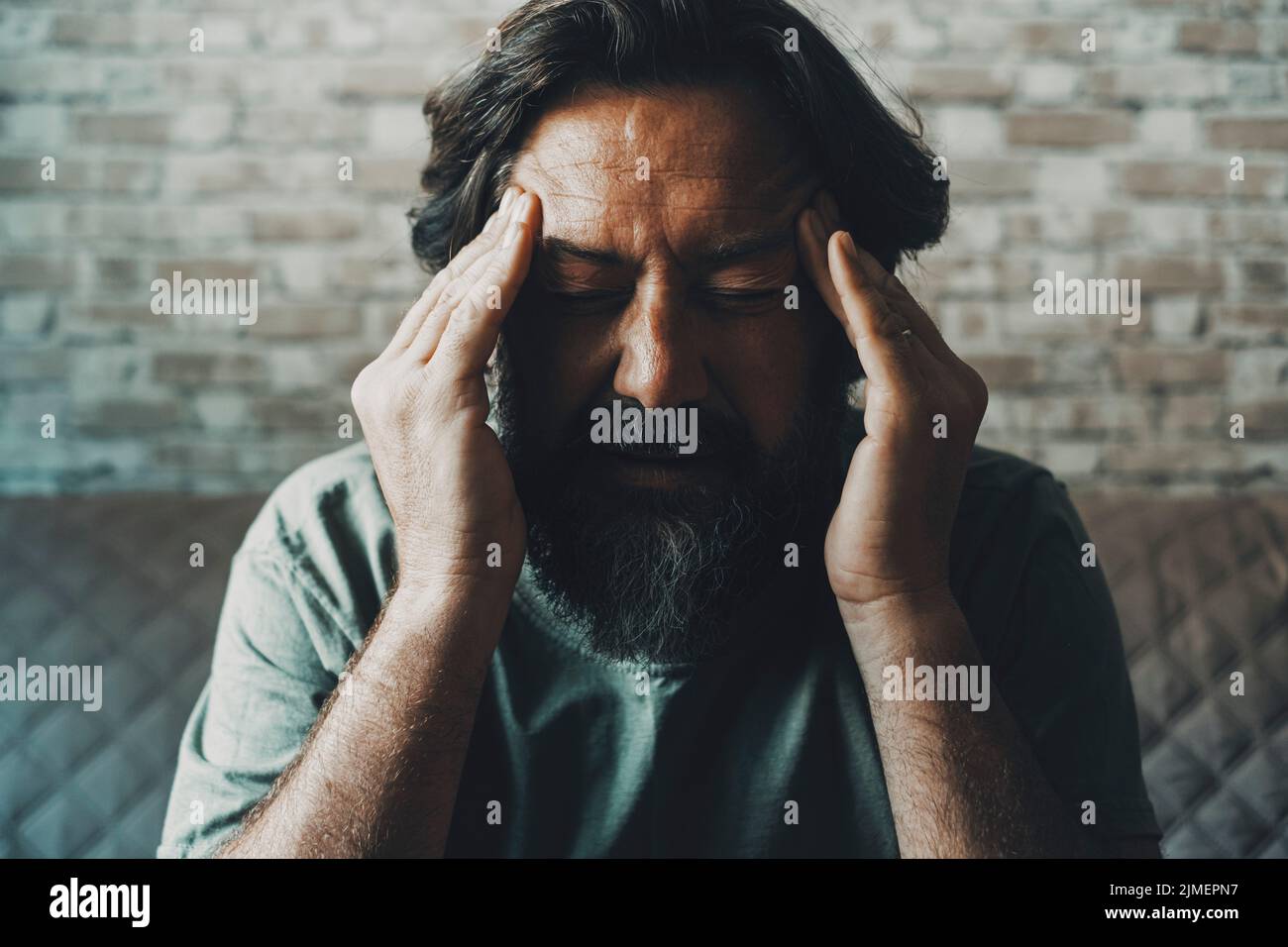 Close up portrait of man touching his head and temples for headache or problems to solve. Bad ...