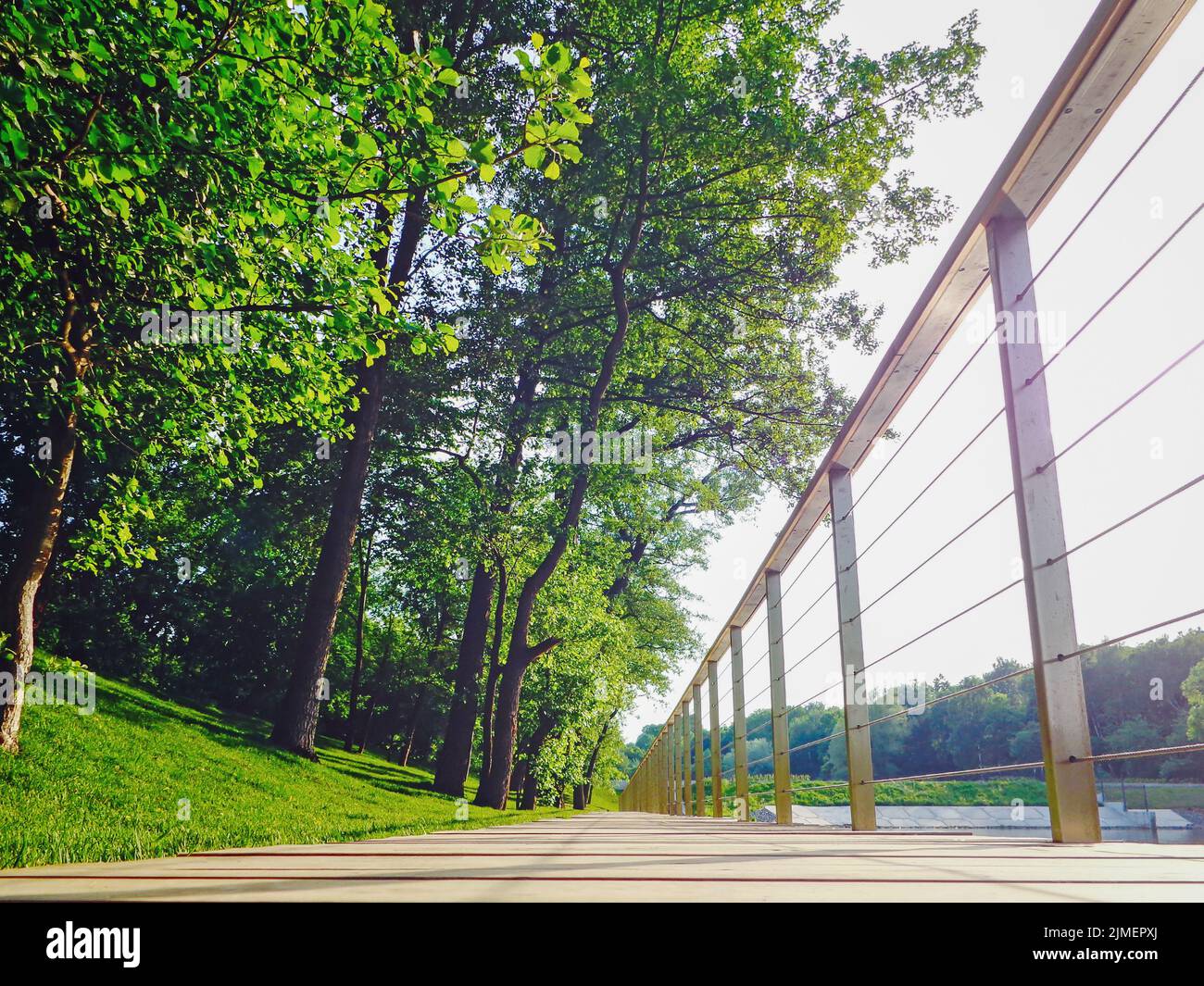 Wooden walking path with railings in green city park Stock Photo - Alamy