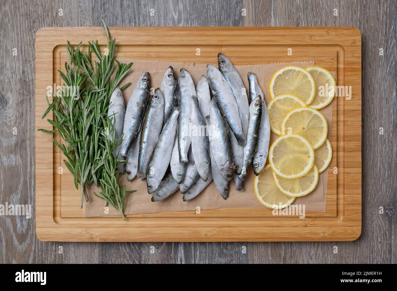 Frozen sprats on a kitchen board with lemons and rosemary Stock Photo ...