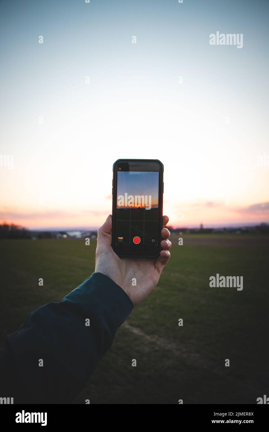 young man with a technical background photographs a sunset with his ...