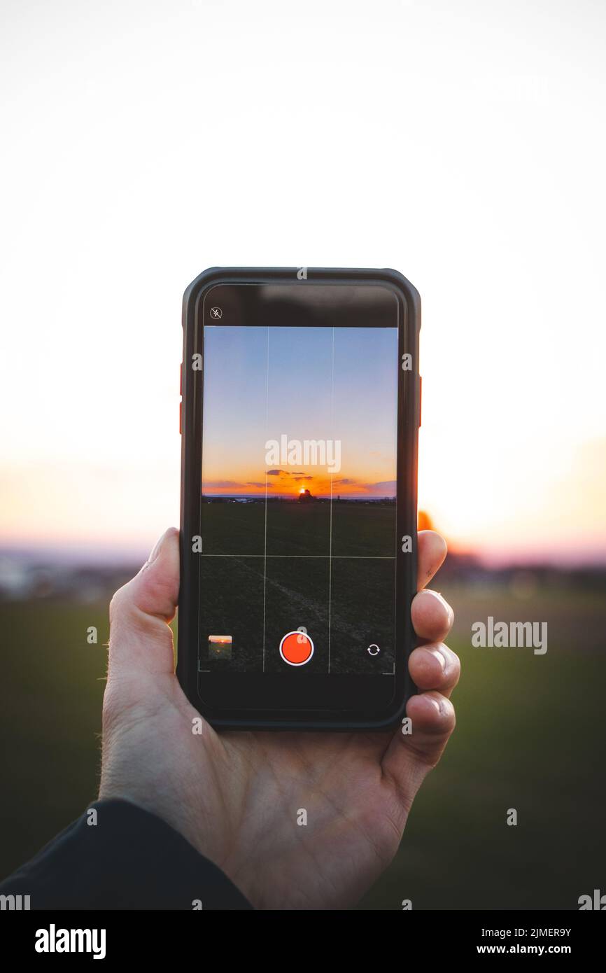 young man with a technical background photographs a sunset with his ...