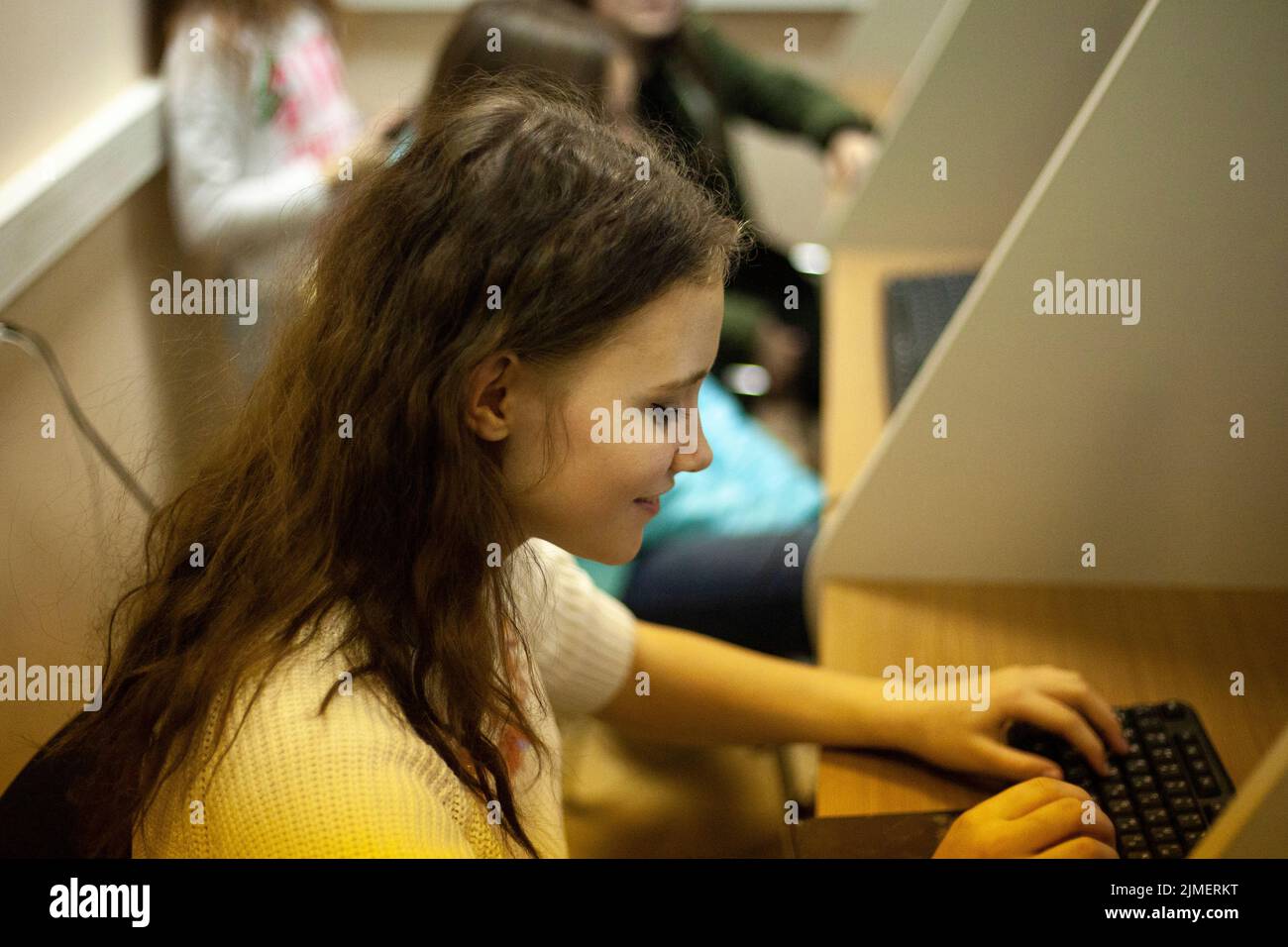 Girl works at computer. Student in classroom. Student types on keyboard ...