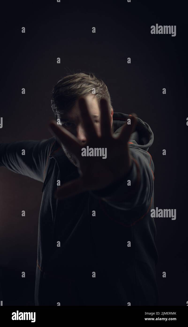 A vertical shot of Caucasian man blocking the camera with his hand in ...