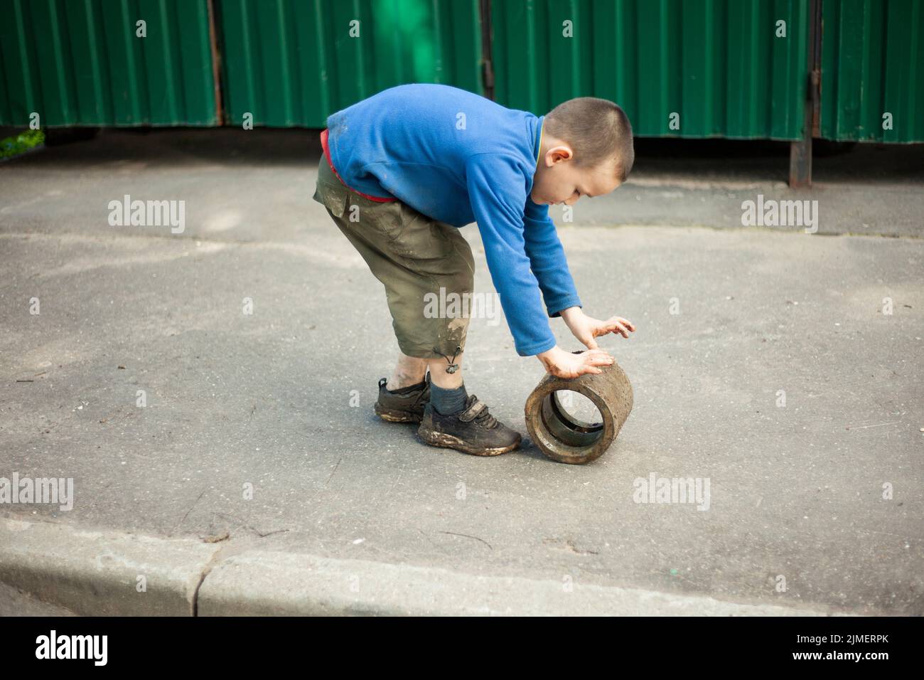 Child is holding dirty object. Little boy plays with concrete ring ...