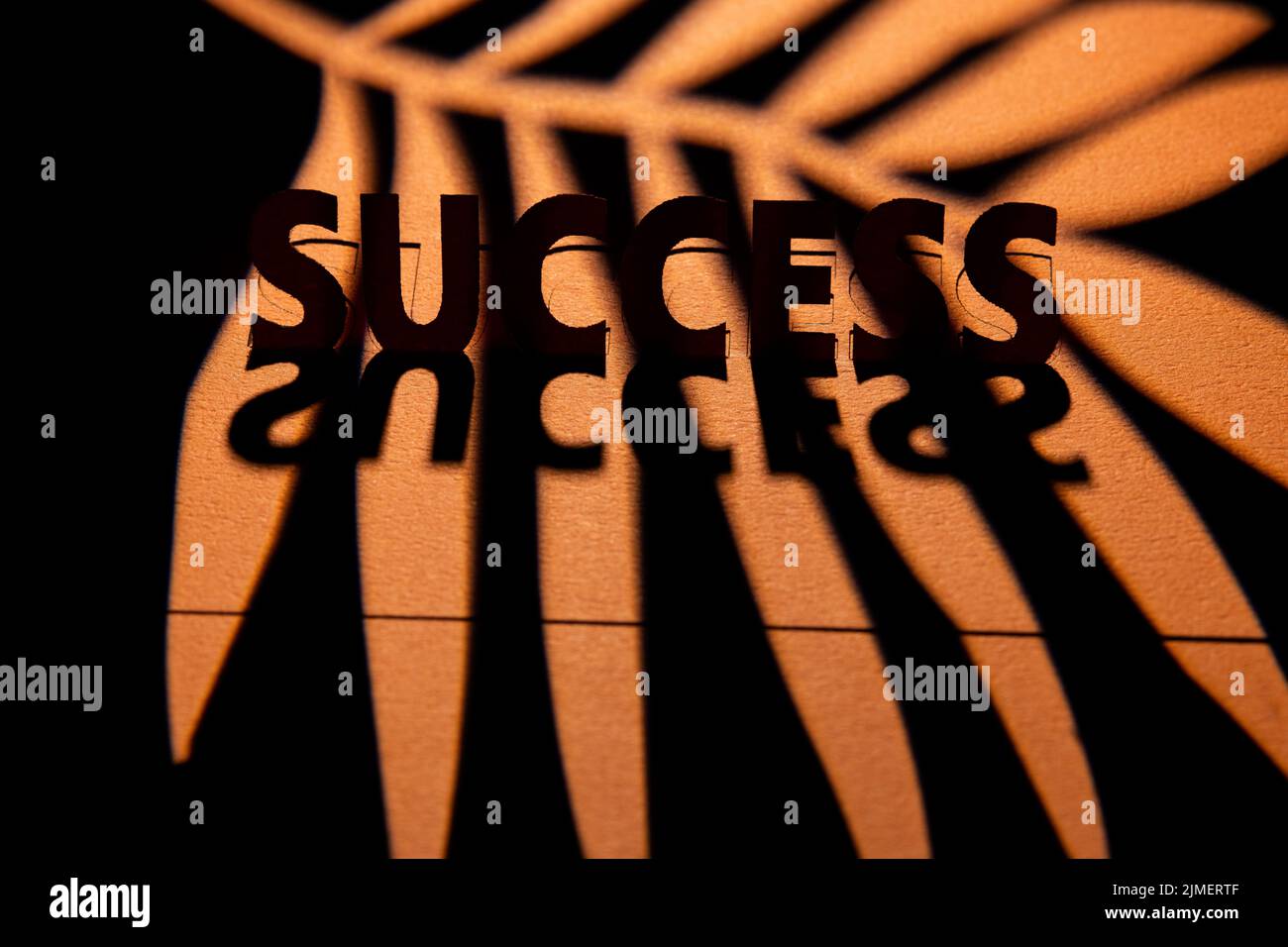 Success word cutting and standing from paper, lit from behind and ...