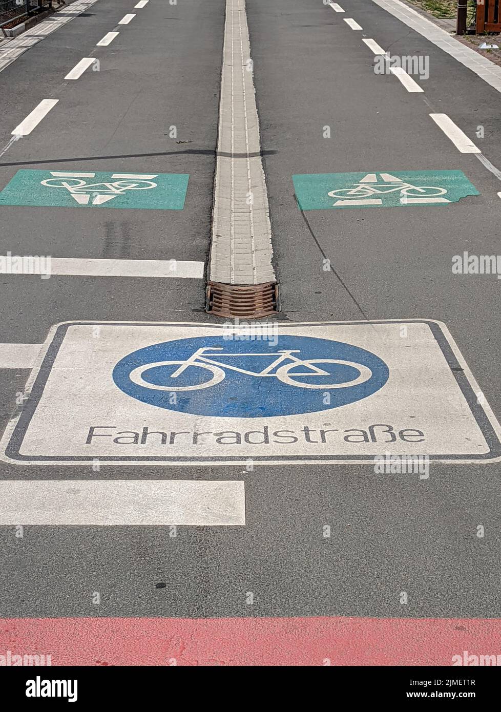 A vertical shot of bicycle signs on the asphalt bike lane with drainage ...