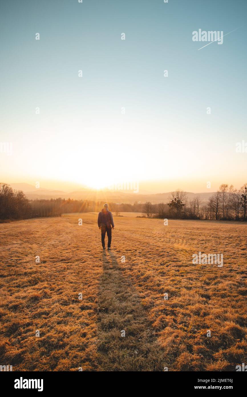 Young ambitious tourist walks through the grain fields at sunset in the ...