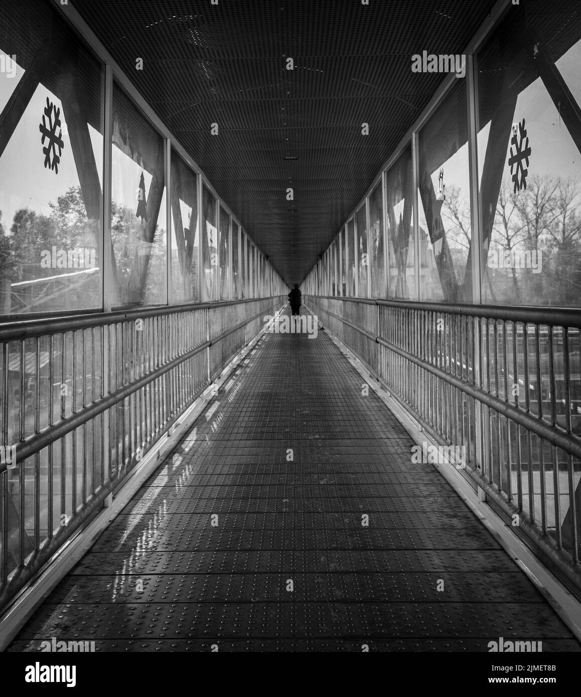 A vertical greyscale of an old pedestrian bridge with glass windows ...