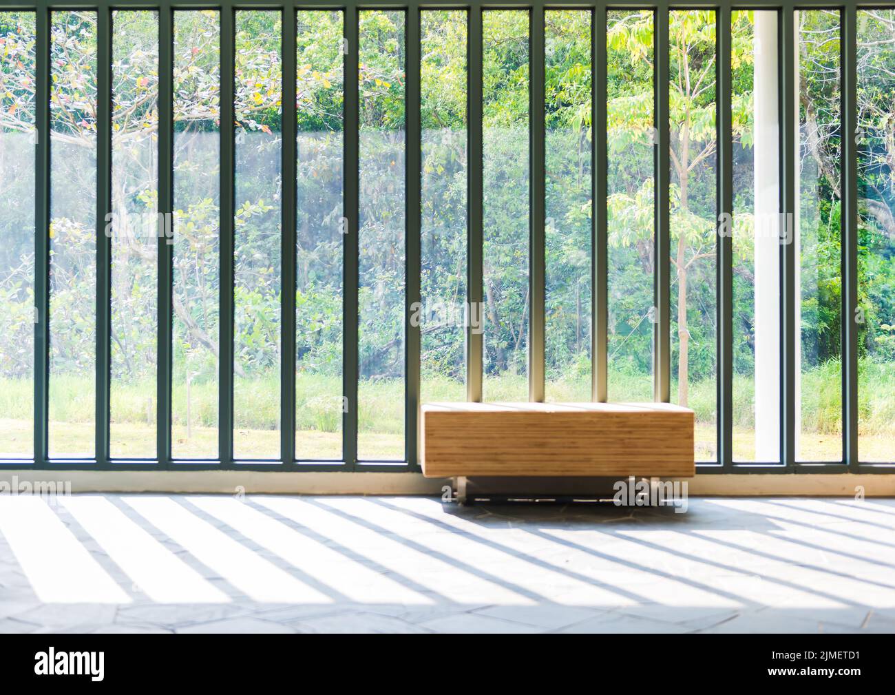 Wooden bench in front of French window with sunlight and countryside ...