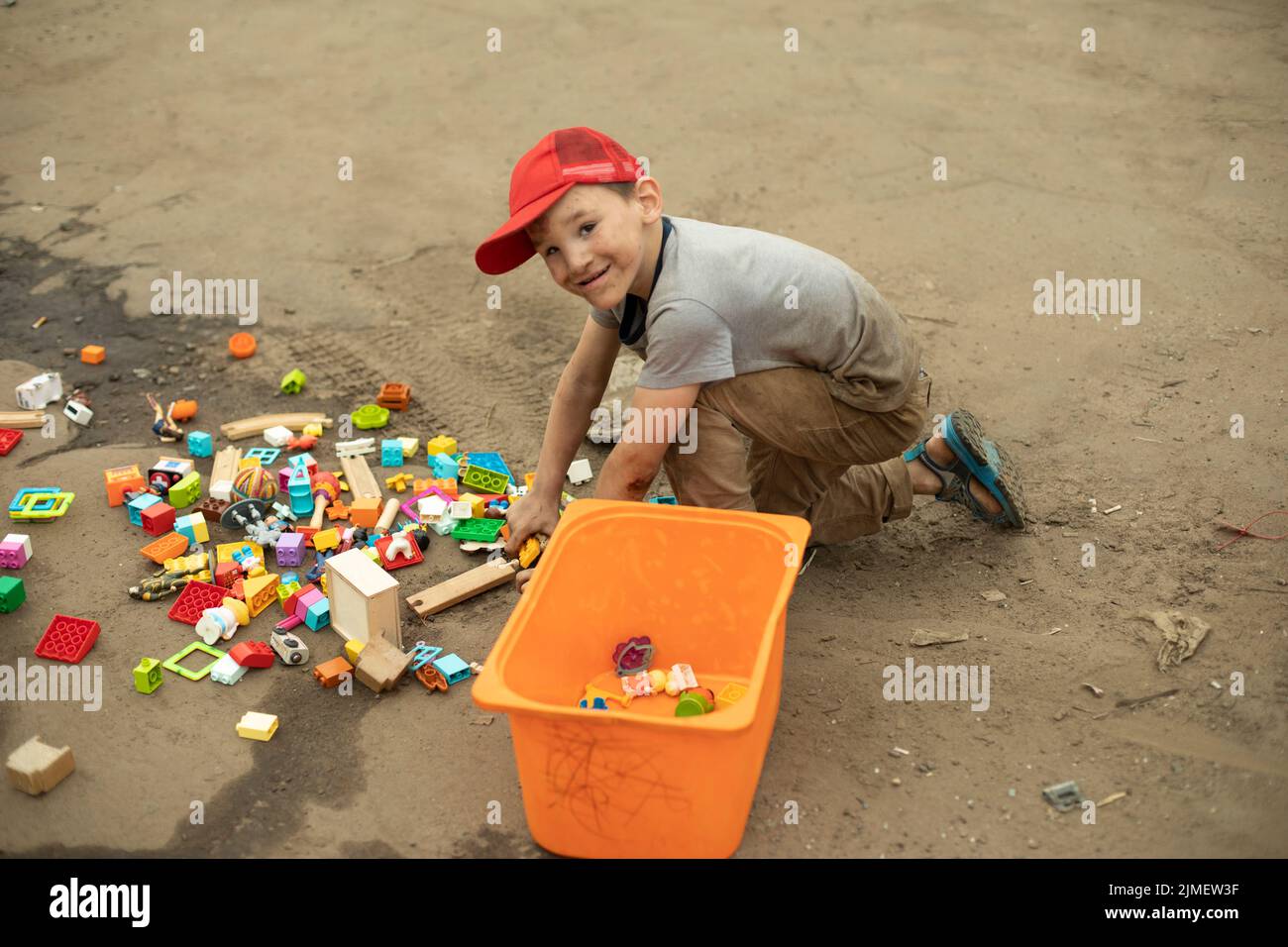 Child with box of toys. Boy scattered toys. Child on street Stock Photo ...