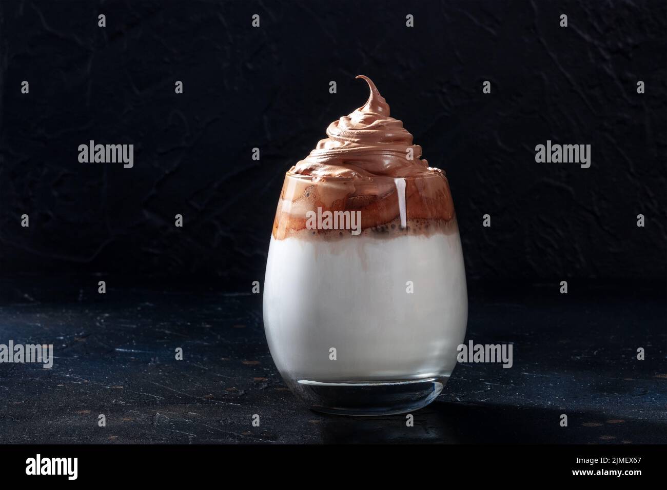 Dalgona cold coffee in a glass on a black background. Sweet Korean ...