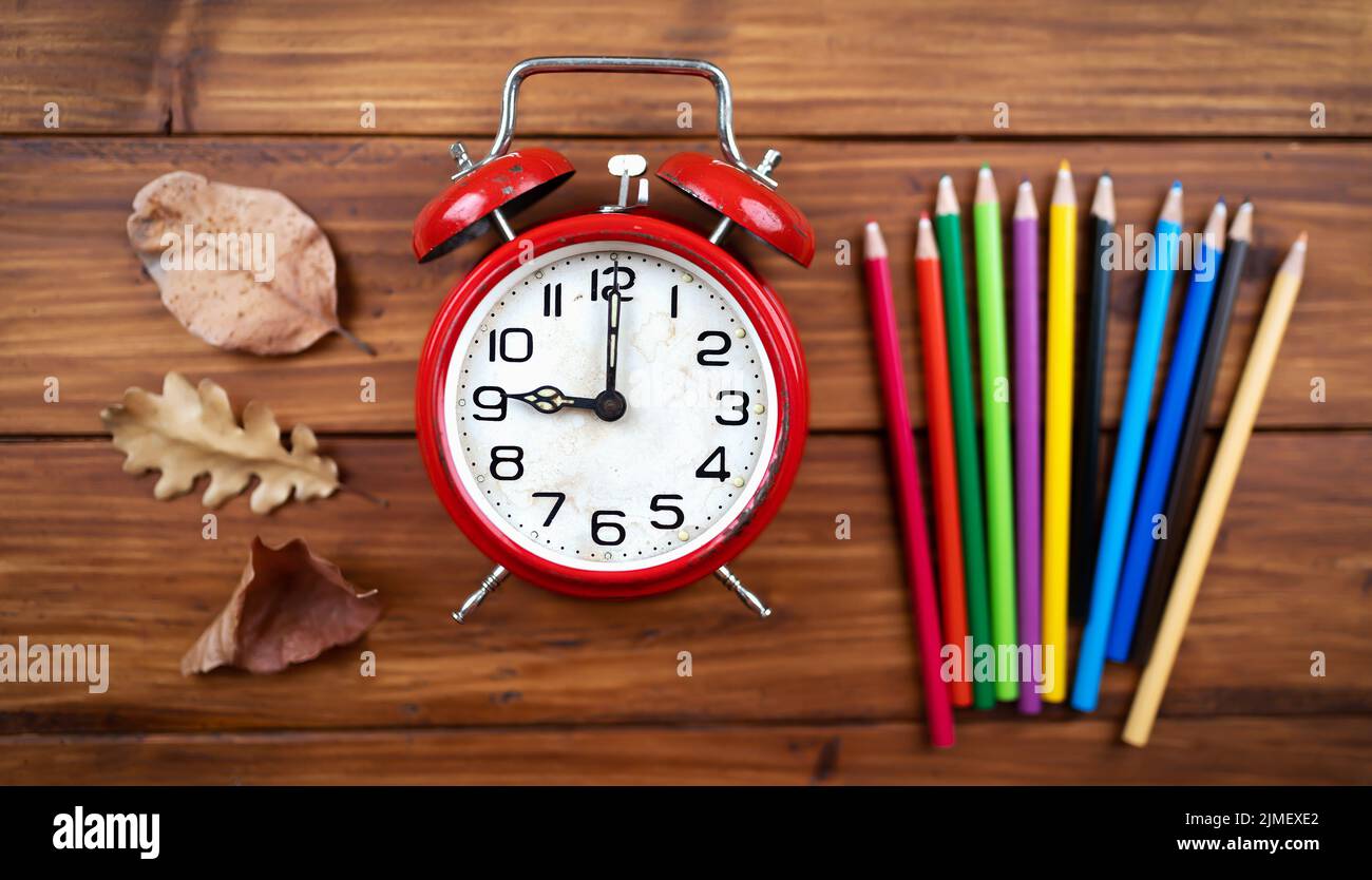 Vintage retro alarm clock, colorful pencils and autumn leaves, back to ...
