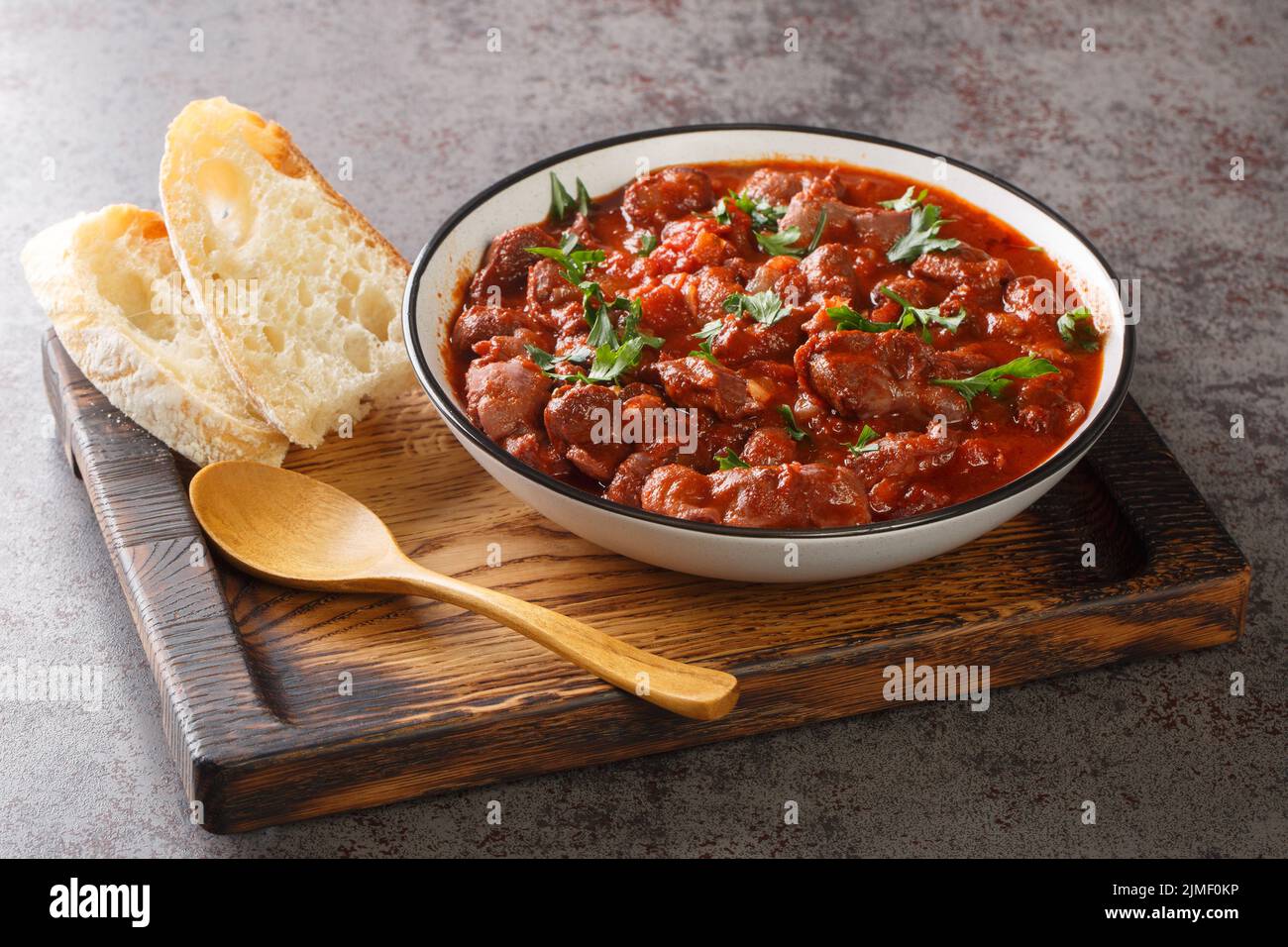 Stewed chicken gizzards in a spicy tomato sauce close-up in a bowl on a ...