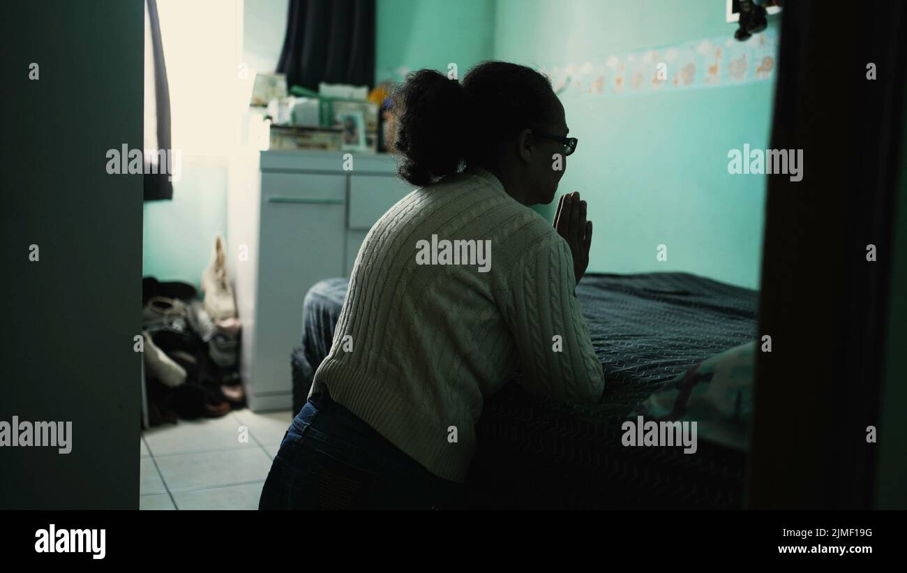 One hispanic older woman praying by the bedside. Religious elder person in FAITH prayer Stock ...