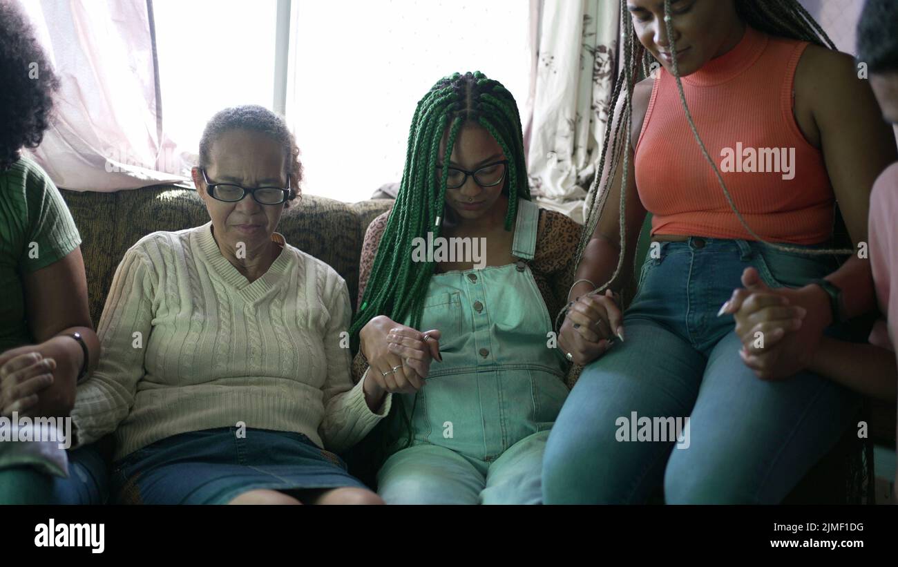A hispanic family praying at home together. South American people in ...