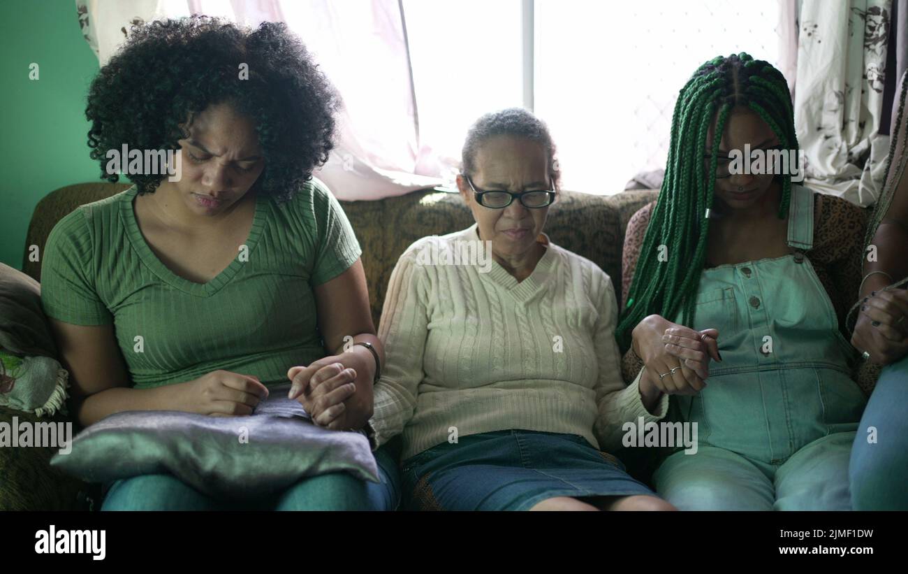A hispanic family praying at home together. South American people in ...