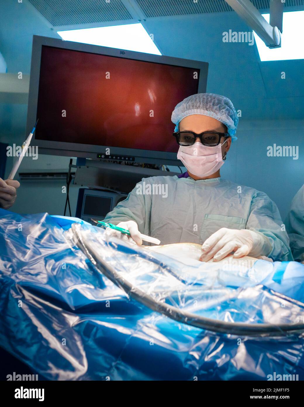 Female surgeon with a scalpel over the patient's body in the operating ...