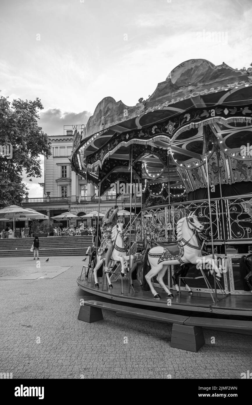 A grayscale shot of the classic carousel with horses on the Plac ...