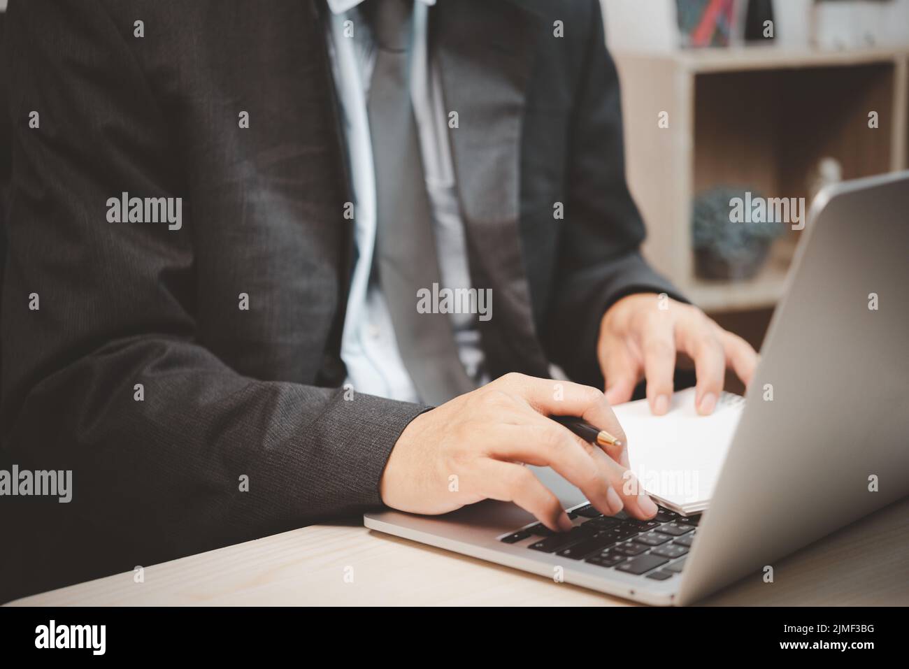 Man person using keyboard computer laptop holding pen and book on desk ...