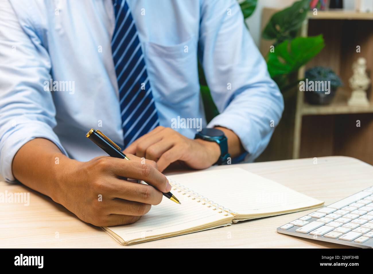 Man hand holding pen write note diary on book Stock Photo - Alamy